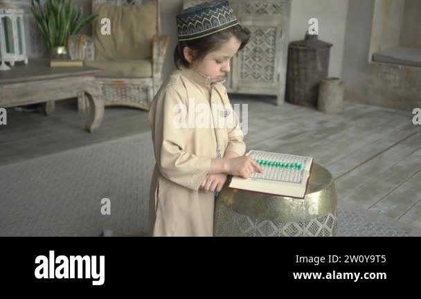 Adorable boy in prayer hat and arabic clothes with rosary beads reading ...
