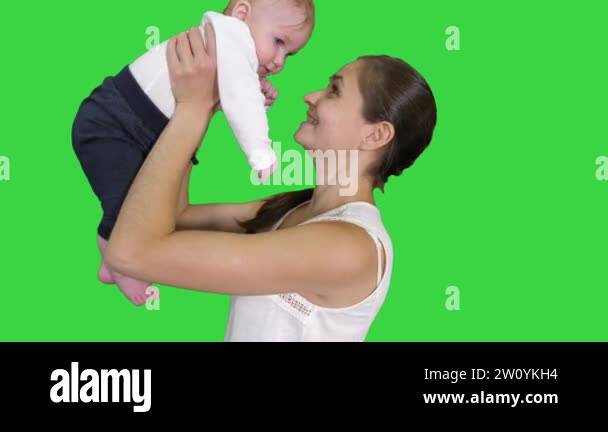 Positive little cute boy with beautiful mom rising her baby up on a ...