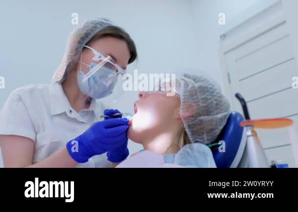 Dentist puts cotton plugs in womans mouth dry teeth during ultrasonic ...