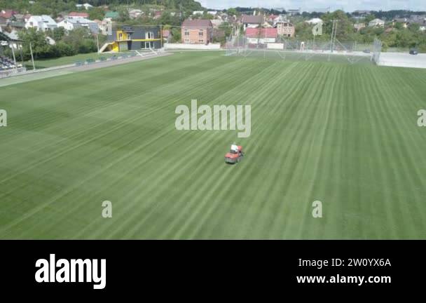 Maintenance of a football Field. Lawn mower cutting green grass. Aerial ...