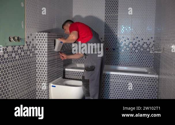 skilled worker man install toilet flush button in new modern bathroom ...