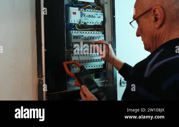 Electricians hands testing current electric in control panel ...