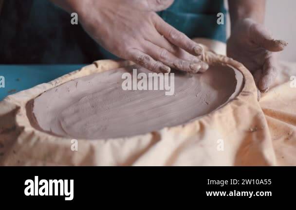 potter forming clay into a dish by using a form and tools to get the ...