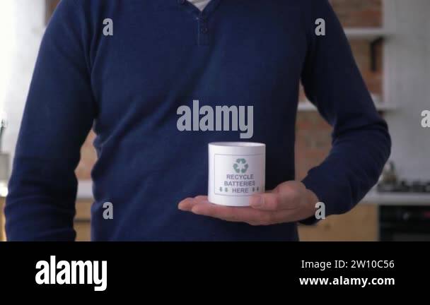 collecting used batteries, man puts old batteries into container with ...