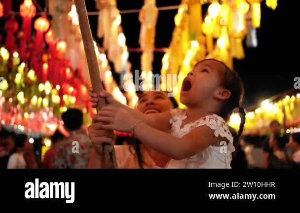 Happy Asian family hanging a thai lanna lantern to make a wish in Yi ...