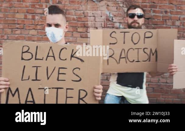 Four Caucasian men stand against a red wall with cardboard posters in ...