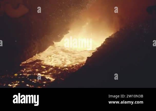 Boiling liquid metal is poured out of a blast furnace. Bright sparks ...