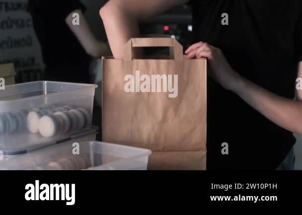 pastry girl in black uniform puts boxes of fresh macaroons in a large ...