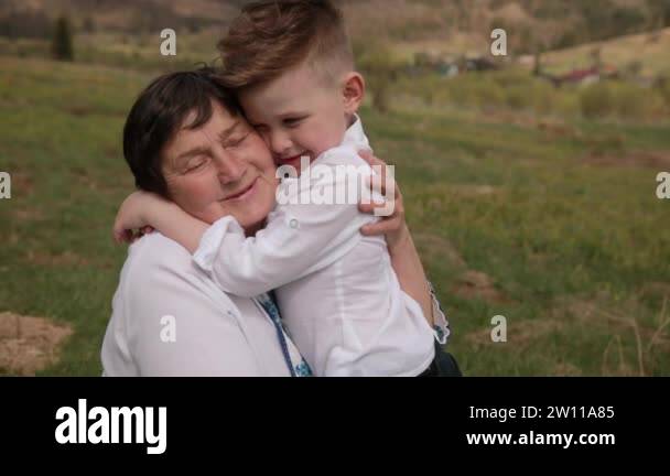 Grandson approaches the grandmother. He puts his arm around her neck ...