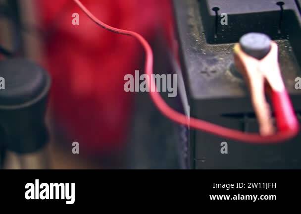 The car battery is charging. Only the positive terminal is visible in ...