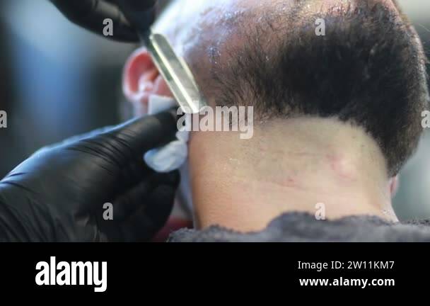 Professional barber shaves customer beard with straight razor. Beard ...