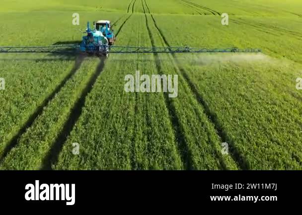 Aerial view of the tractor that irrigates the green field by special ...
