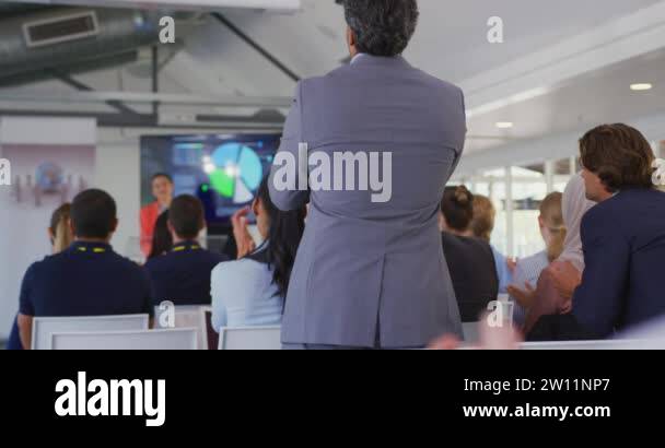 Rear view of the audience standing up from their seats and clapping at ...