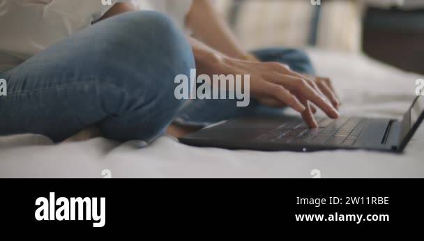 Woman hands typing something on a laptop keyboard in the bedroom. Slow ...