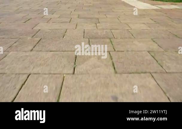 movement along a paved pedestrian walkway. unrecognizable people walk ...