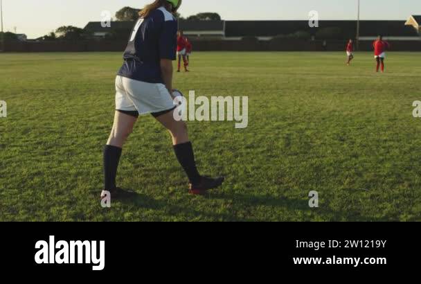 Rear view of a young adult Caucasian female rugby player wearing a headguard making a drop kick ...