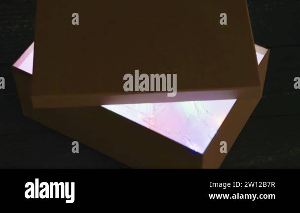 woman opening mystery box in the dark and revealing bright light coming ...