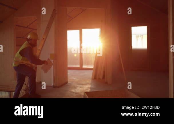 LENS FLARE: Young builder climbs up ladder into sunlit floor under ...