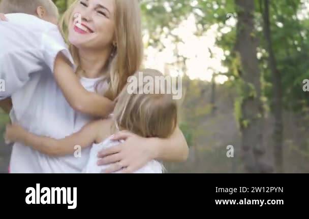 Back view of cute little girl and boy hugging mother. Woman laughing ...