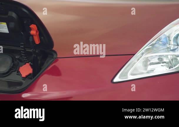 Man hand open and plugging in Tesla electric red car at super charging ...