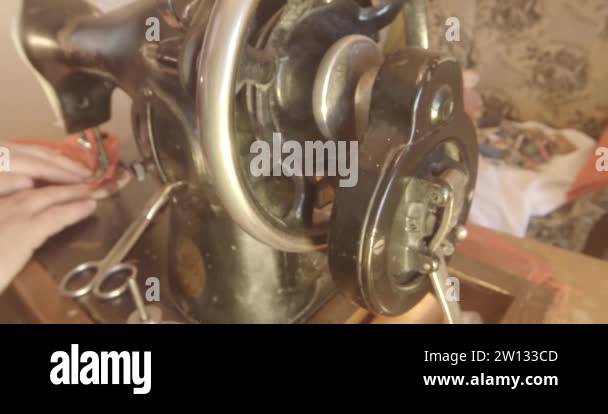 grandmother sews a red flag on an old sewing machine of the Soviet ...