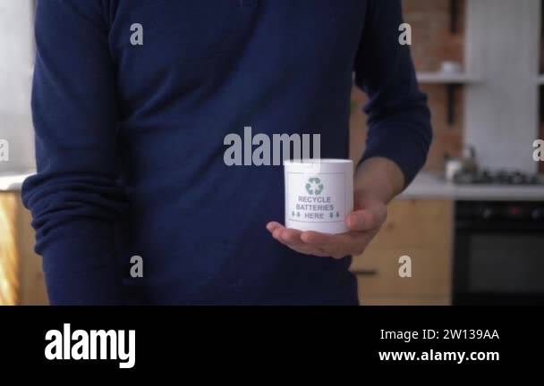 life without waste, male hands places old batteries into container for ...
