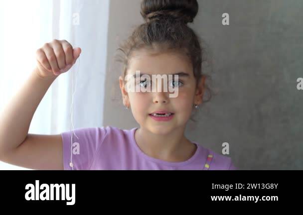 Portrait of a smiling toothless child holding a tooth on a string ...