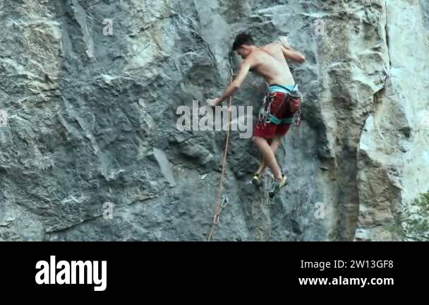 back view young muscular man rock climber climbing on tough sport route ...