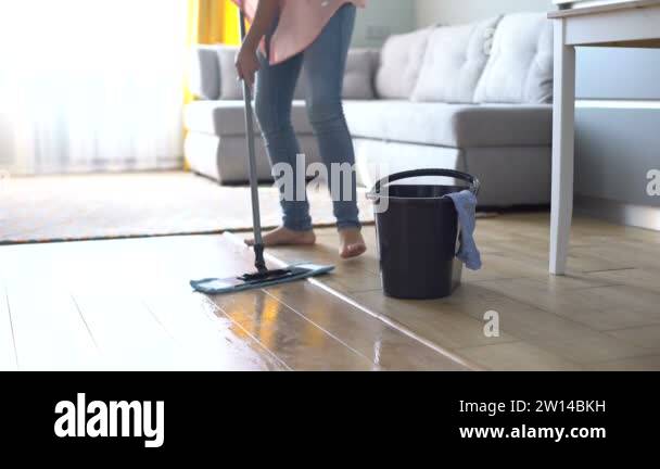 Barefoot girl mopping floor, maintaining cleanliness and hygiene in ...