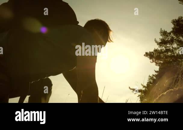 backpackers help climb each other up the hill. father holds out his ...