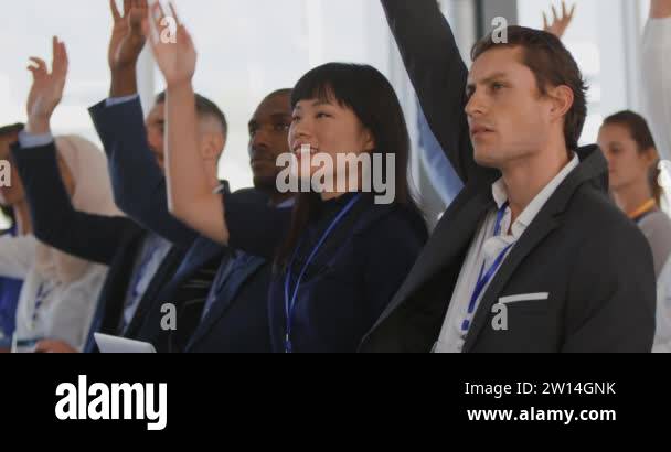 Close up side view of a diverse audience at a business seminar raising ...