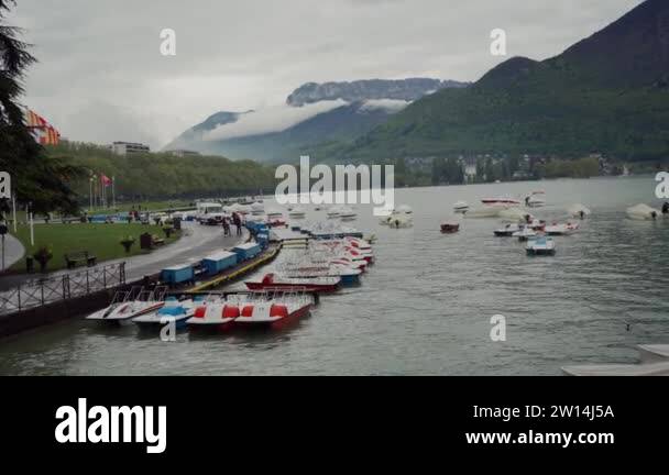 Lake Annecy view with tourists walking on the Promenade Jacquet, boats ...