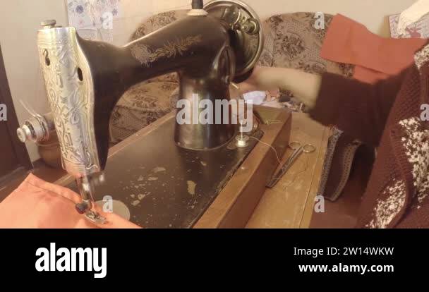 grandmother sews a red flag on an old sewing machine of the Soviet ...