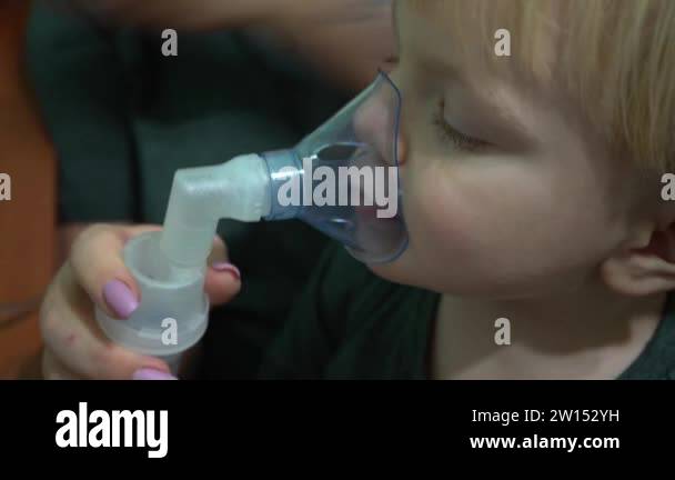 A child of three years old breathing in an oxygen mask. Inhalation of ...