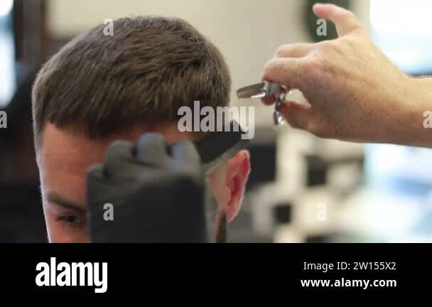 Barber cuts the hair of the client with scissors. Close up. Attractive ...