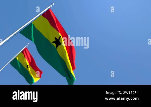 The national flag of Ghana is flying in the wind against a blue sky ...