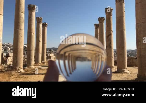 Hand holding crystal ball over ancient roman ruins in archeological ...