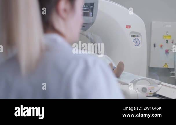 Woman lying on the CT or MRI scanner during machine imaging her body, lights up infrared rays ...
