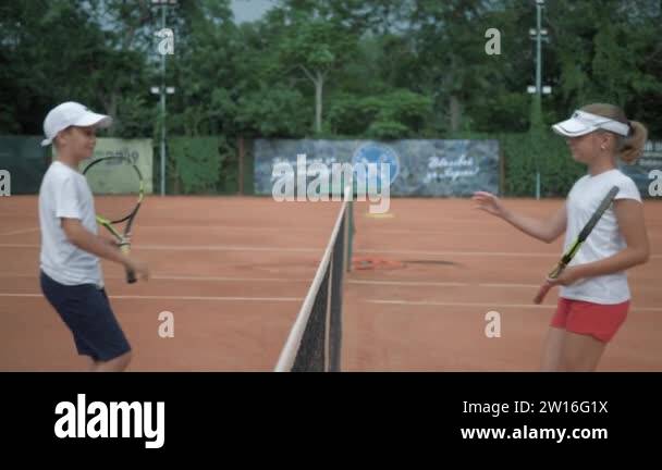 Start of tennis match, girl and boy tennis players meeting by net and ...
