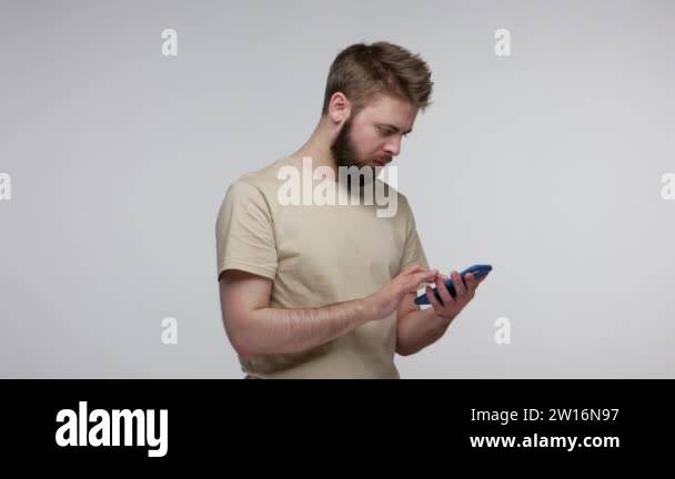 Mobile user, concentrated attentive bearded guy typing message using cellphone to communicate ...