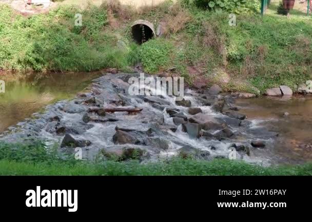 Sewage pipe outflow into river, water pollution and ecology concept ...