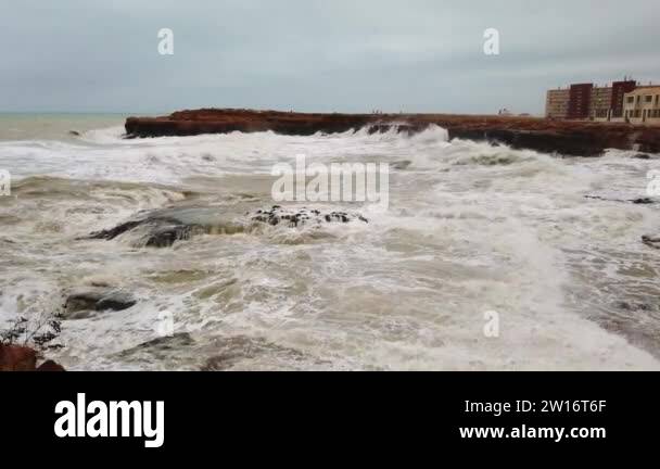 Big wave hitting into rock splashing high with lots of white foam at ...