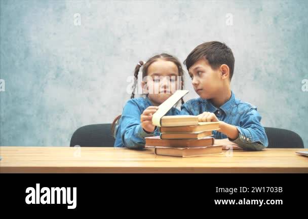 Two kids choosing between stack of books and laptop. Laptop is the ...