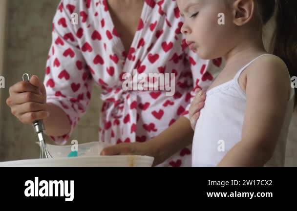 Mom teaches a child to cook dough. Mother and daughter stir with a ...