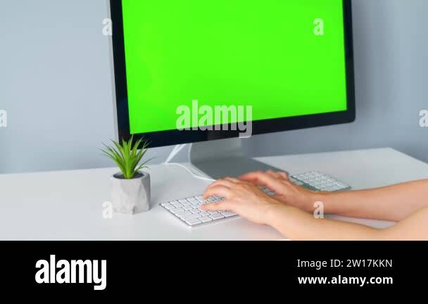Woman typing on a computer keyboard, monitor with a green screen ...