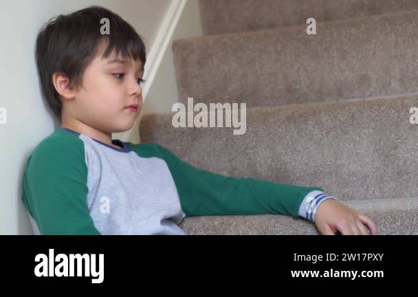 Kid boy with sad face sitting on stair case, Sad child looking down ...