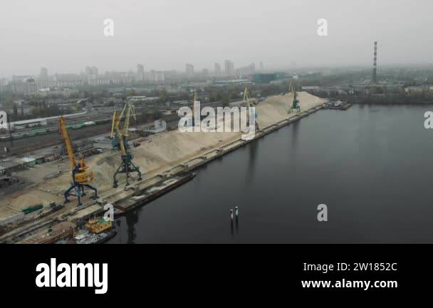 Port working cranes extracting sand from barge and scow in docks on ...