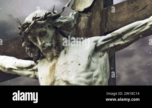 Crucifixion cross with Jesus Christ statue over stormy clouds and Snow falling time lapse as ...
