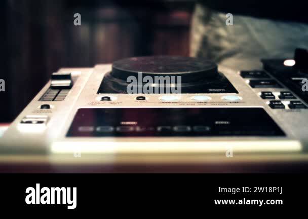 DJ at a console booth spinning and touching mixer faders and knobs ...