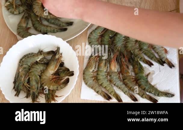 girl prepares shrimp for cooking. soaks and cuts off the antennae in ...